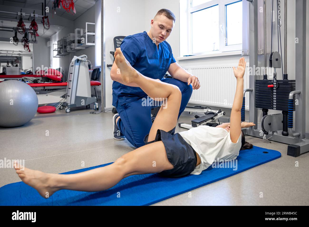 Physical therapist stretching his patient leg while he laying at the ...