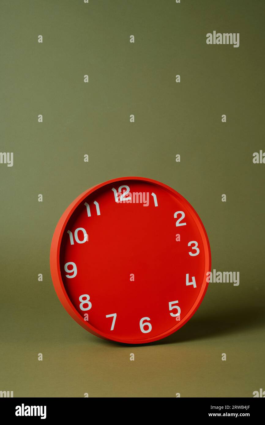 a red clock without hour or minute hands on an olive green background ...