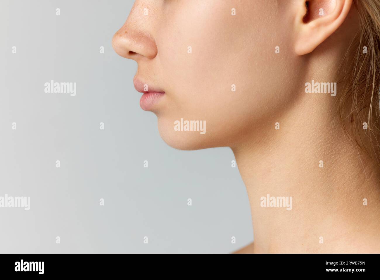 Cropped side view image of female face isolated over grey studio ...