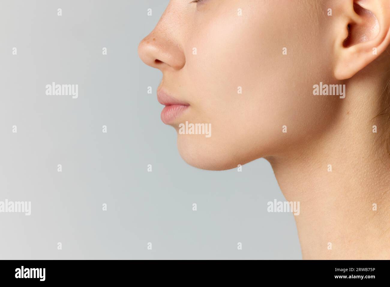 Cropped side view image of female face isolated over grey studio ...