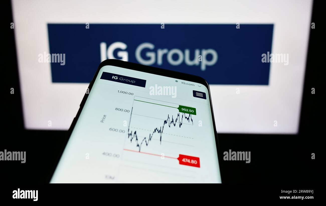 Mobile phone with website of British trading company IG Group Holdings plc on screen in front of ...