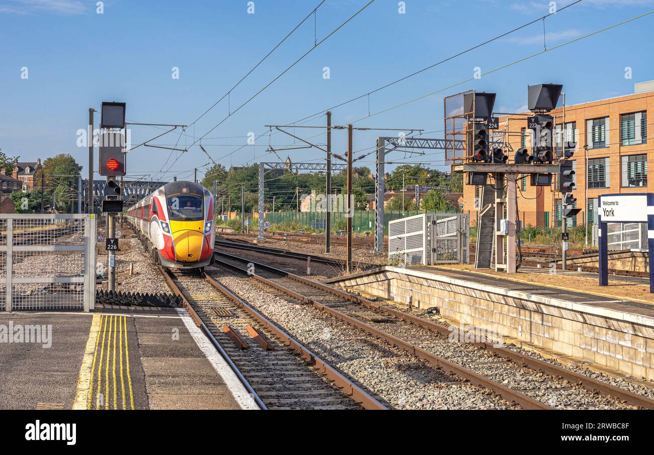 A modern train approaches the platforms of a railway station. A signal ...