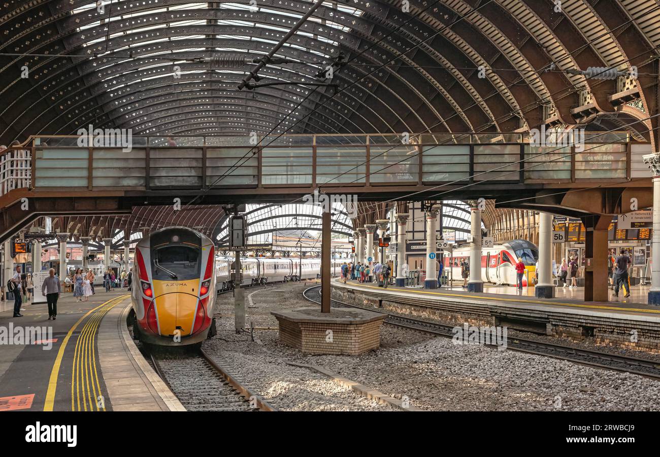 A train arrives at a crowded railway station with a historic iron ...