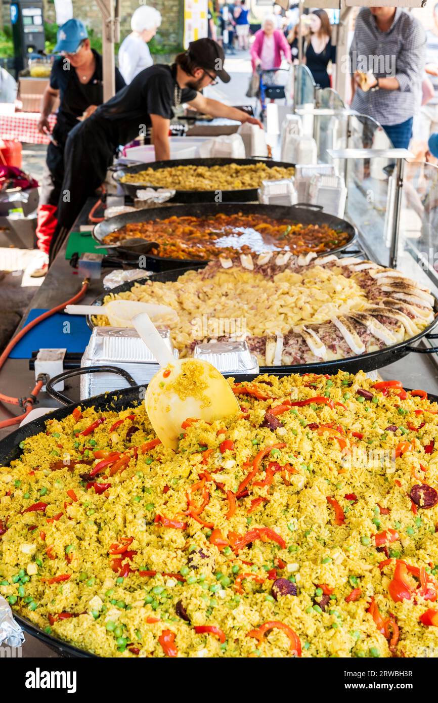 Close up of French food stall selling paella and Tartiflette which is being cooked in massive ...