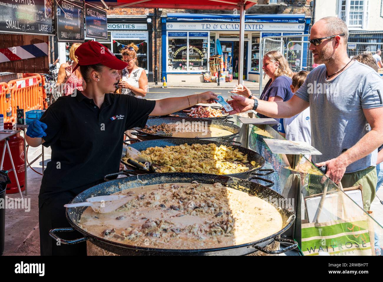 Woman working outdoors on a French food stall handing change over large ...
