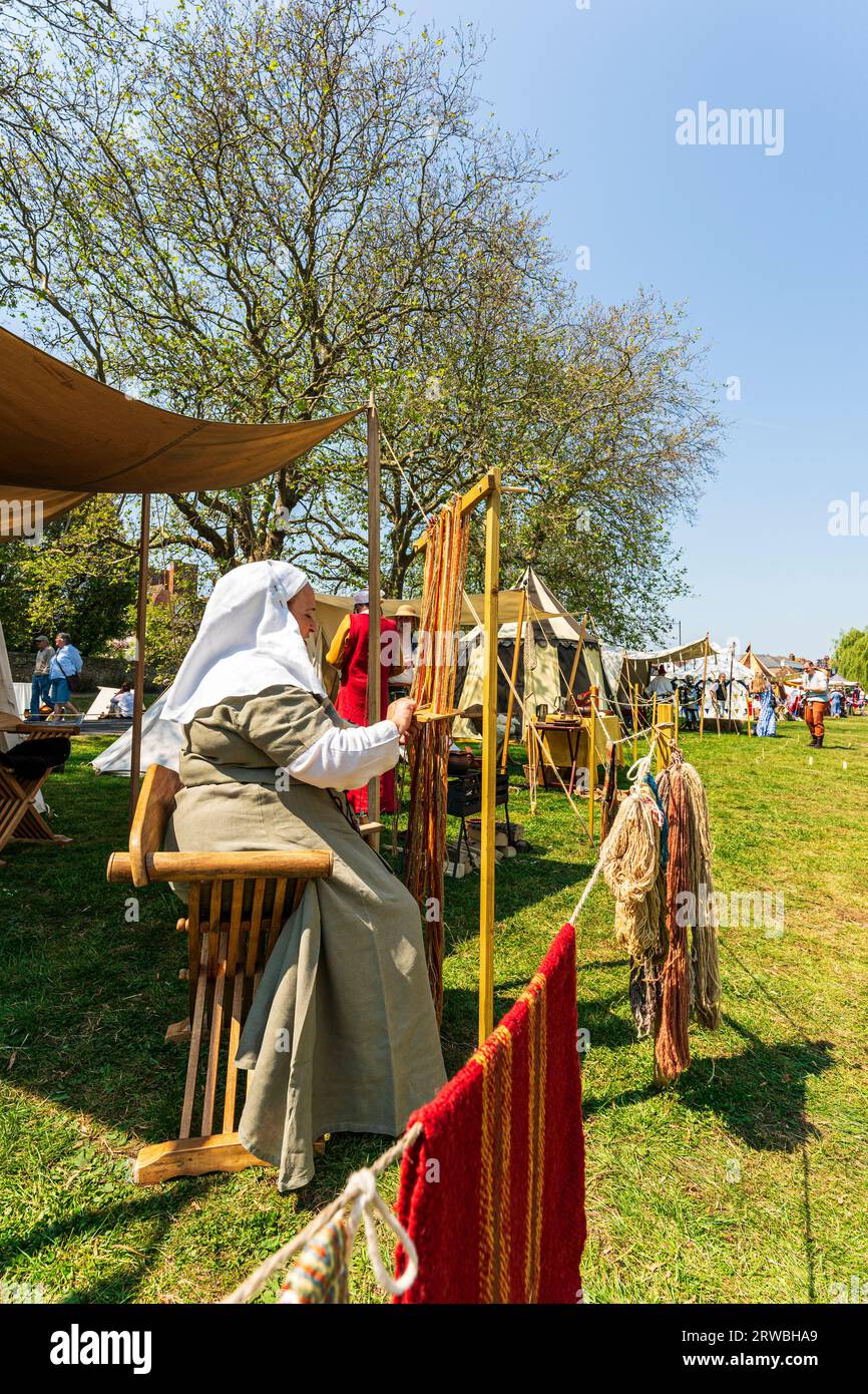 Woman in middle ages period costume, working on a loom weaving threads ...
