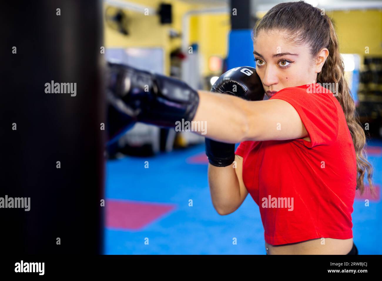 Female boxer training and hitting a punching bag with gloves. Fighting ...