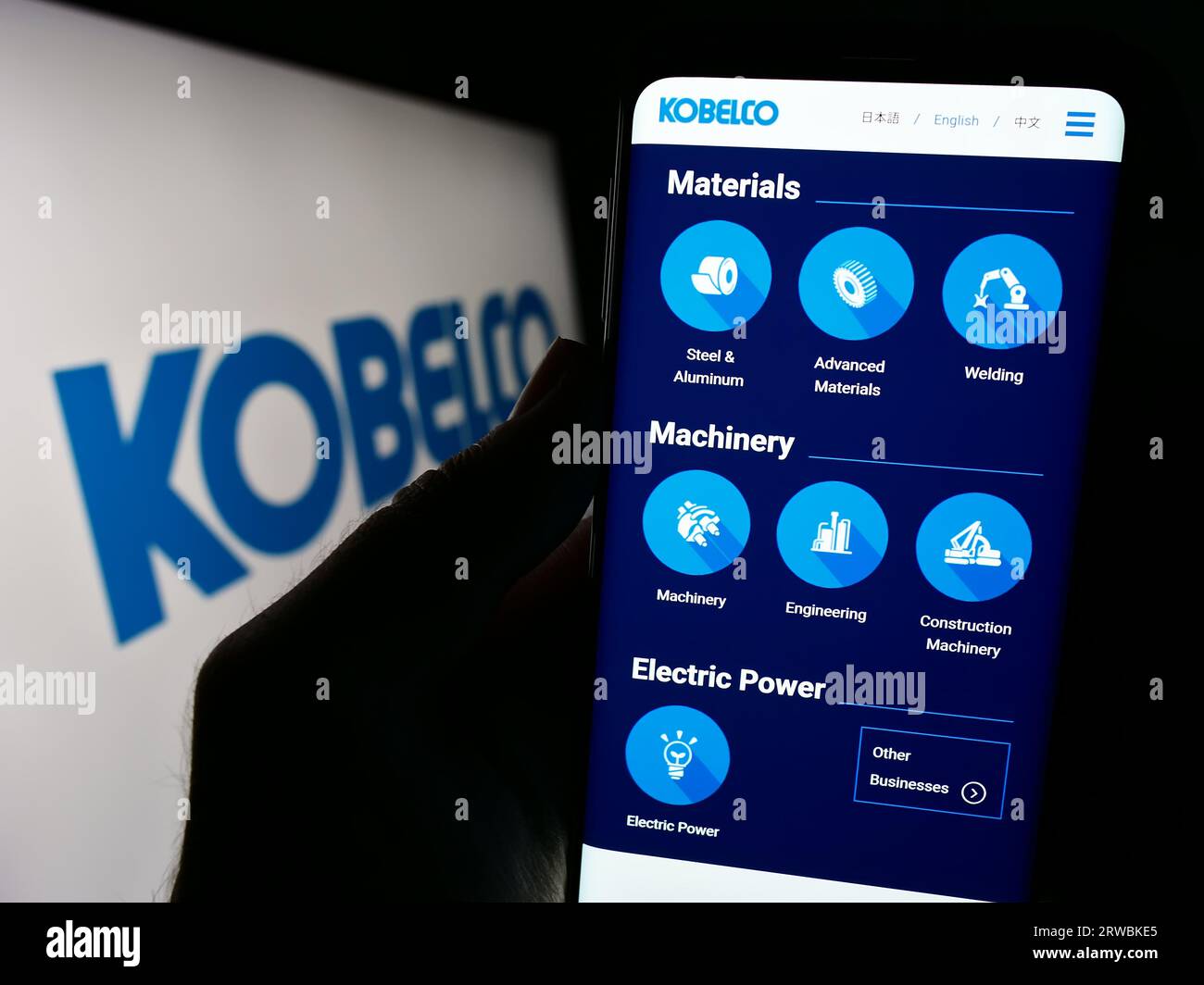Person holding cellphone with website of Japanes company Kobe Steel Ltd ...