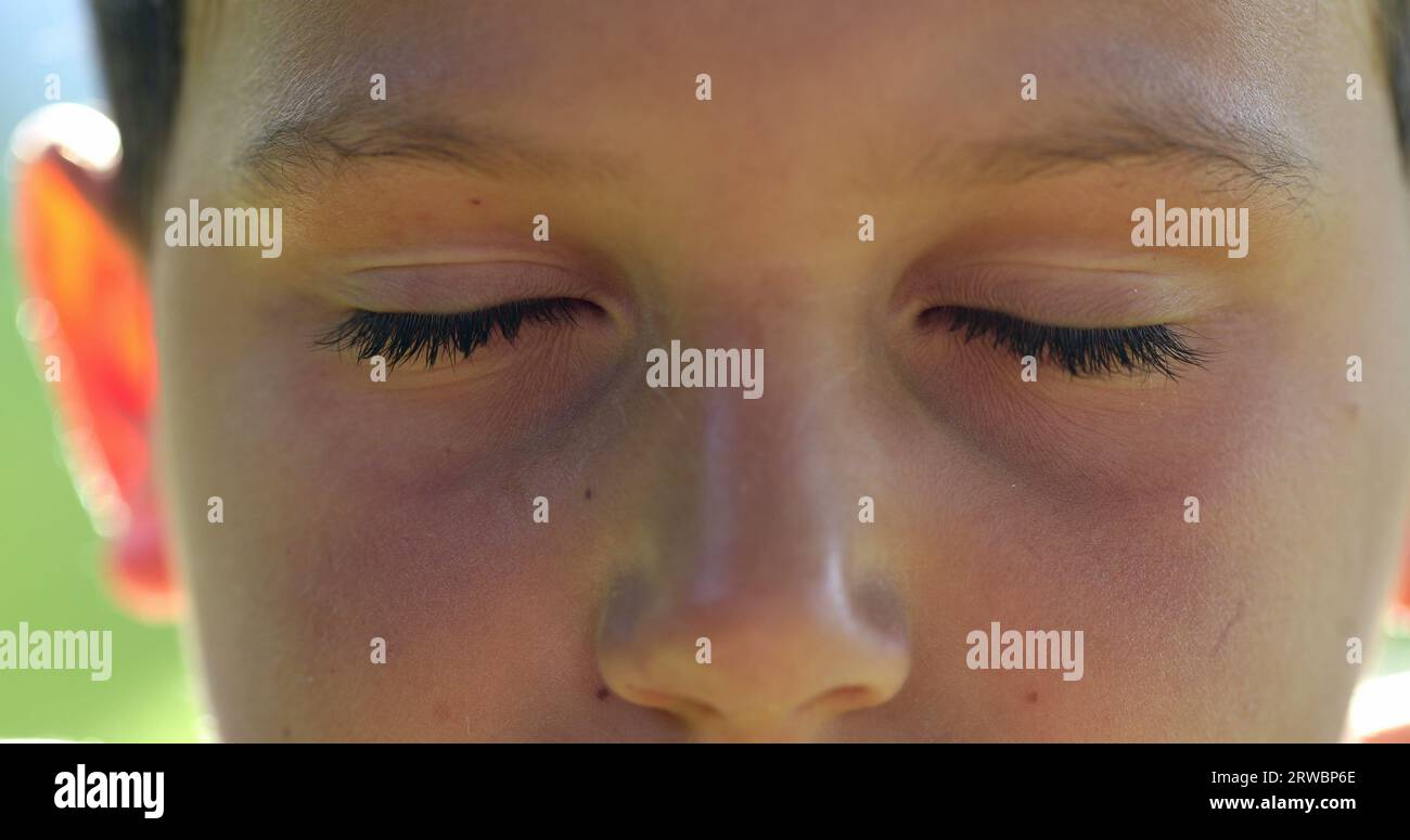 Kid face close-up closing eyes in meditation. Child boy opening eyes ...