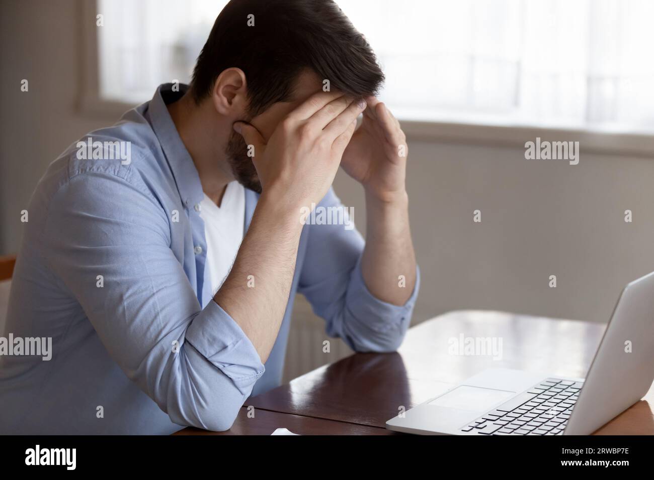 Stressed man touching forehead, looking at laptop screen Stock Photo ...