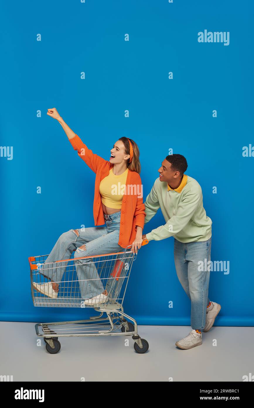 positive african american man riding shopping cart with girlfriend ...