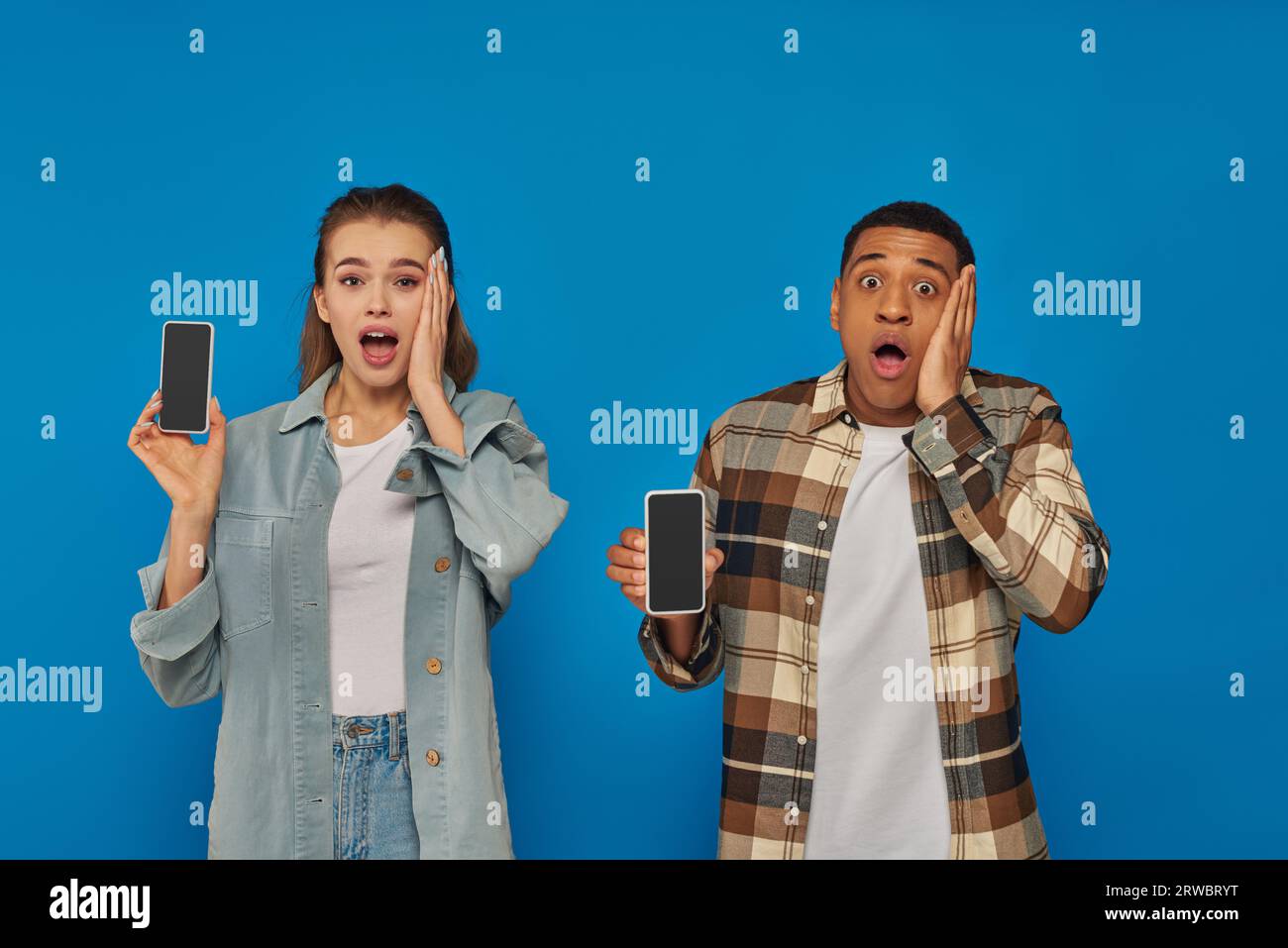 shocked woman and amazed african american holding smartphones with ...