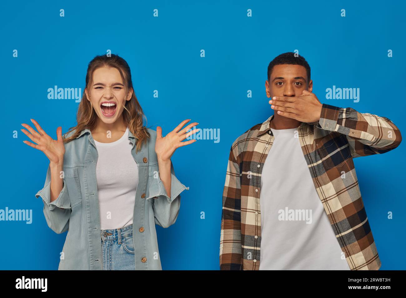 reaction of interracial couple on blue backdrop, emotional woman ...