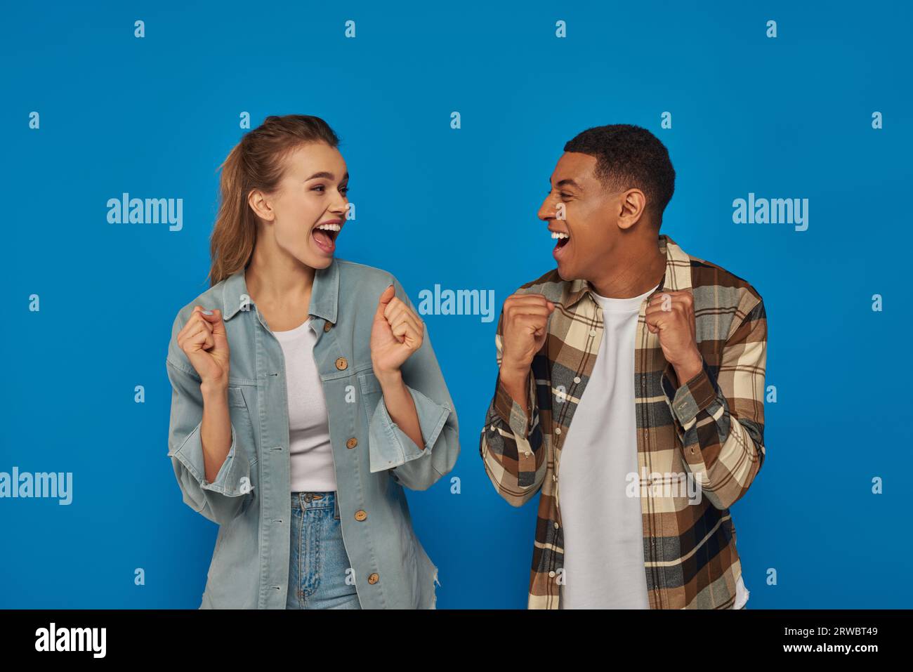 happy interracial couple screaming from joy looking at each other on ...