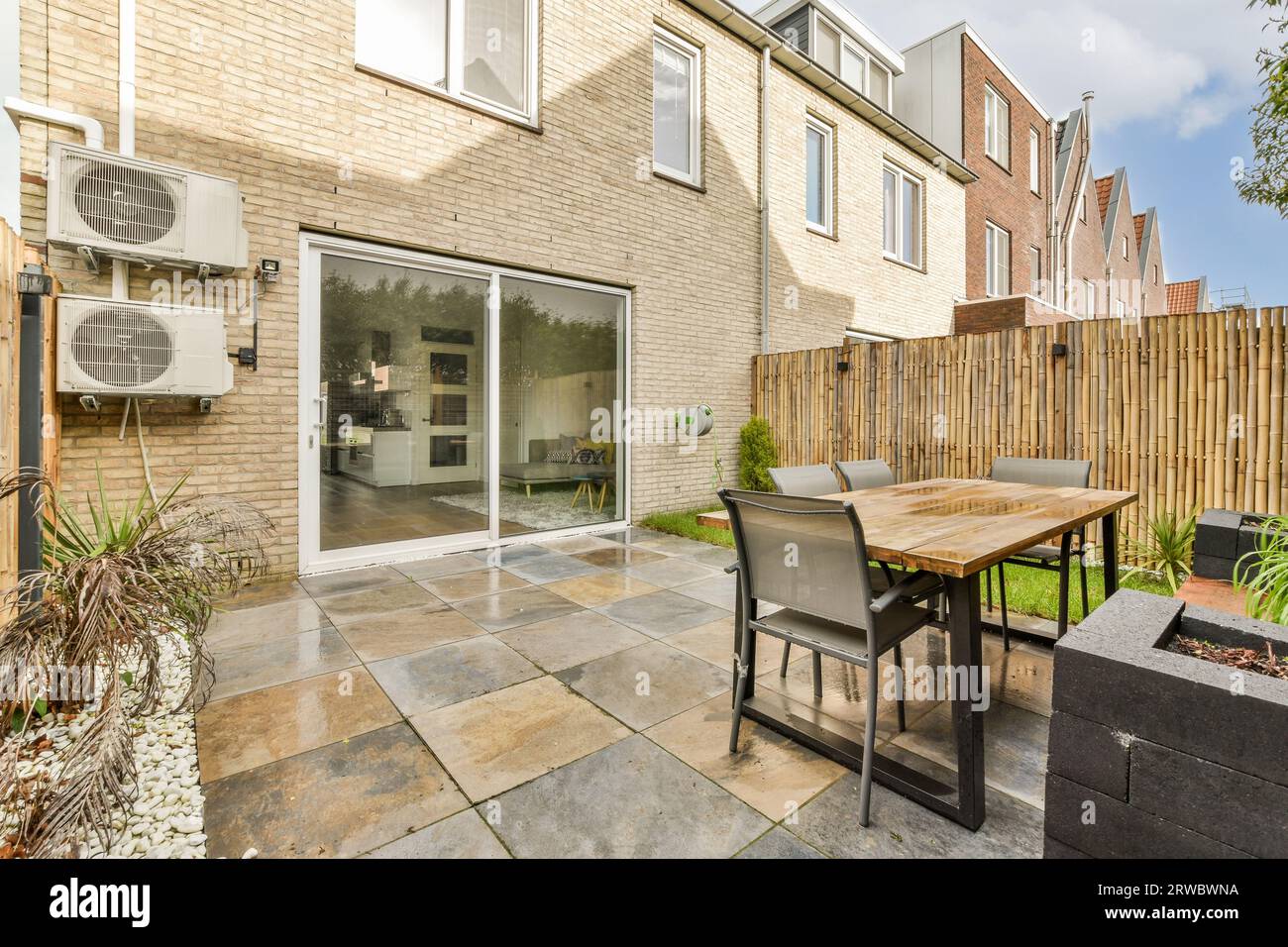 Patio with sitting area placed on wet tiled floor next to wooden fence ...
