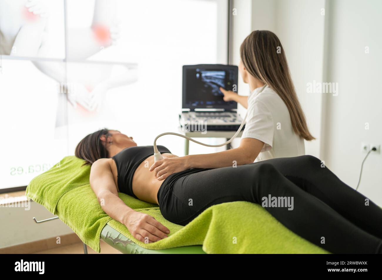 Professional female therapist using ultrasound scan to examine belly of ...