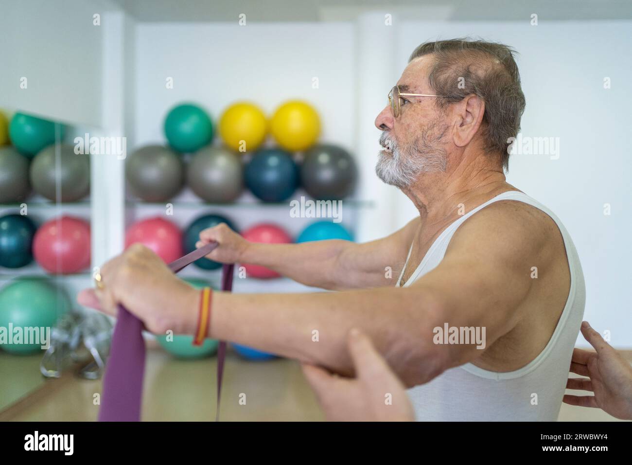 Anonymous therapist helping a senior patient to exercise with elastic ...