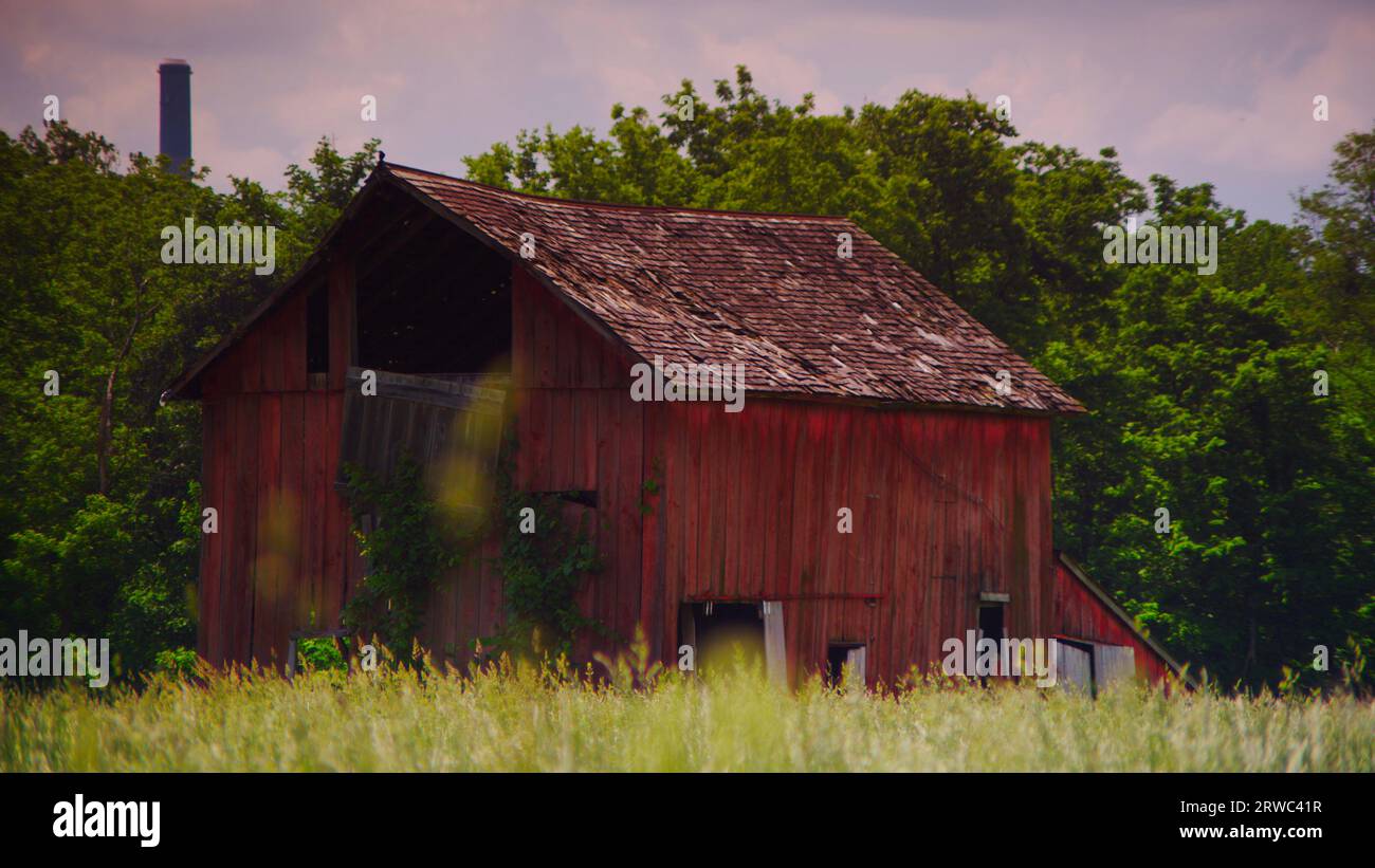 Old barn with a looming but distant power plant stack on an idyllic ...