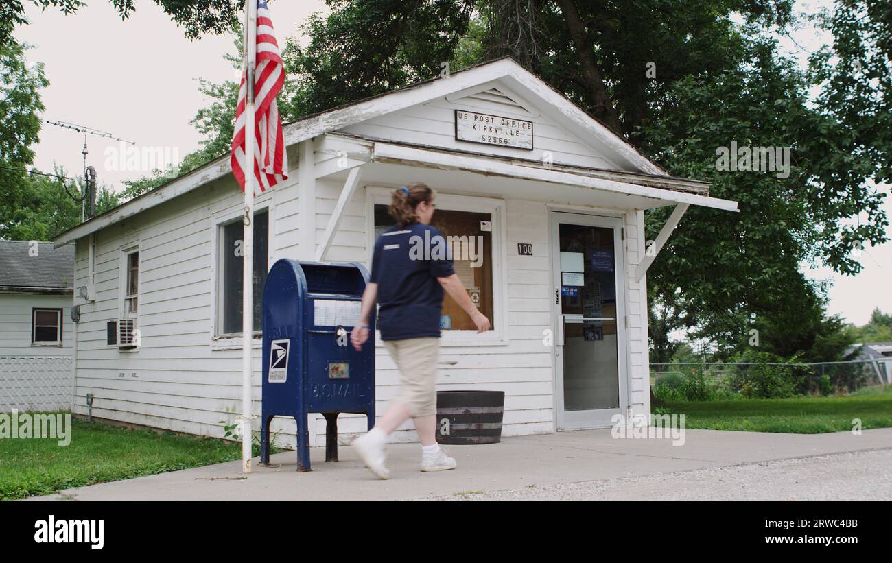 Postal Clerk walks into frame and enters a small town rural Post Office ...