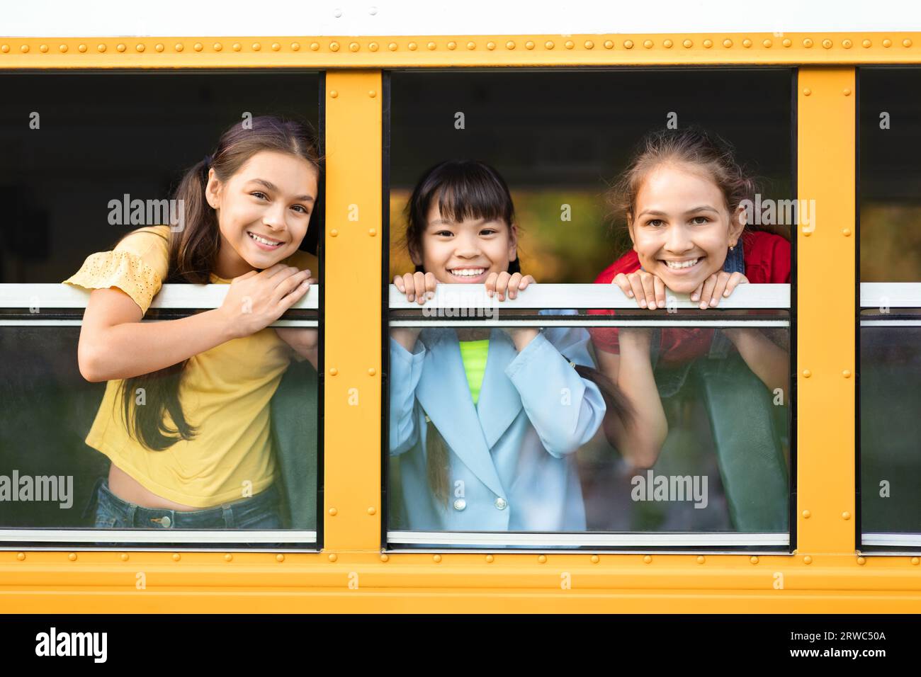 Group of smiling teen girls peeking out of school bus window Stock ...
