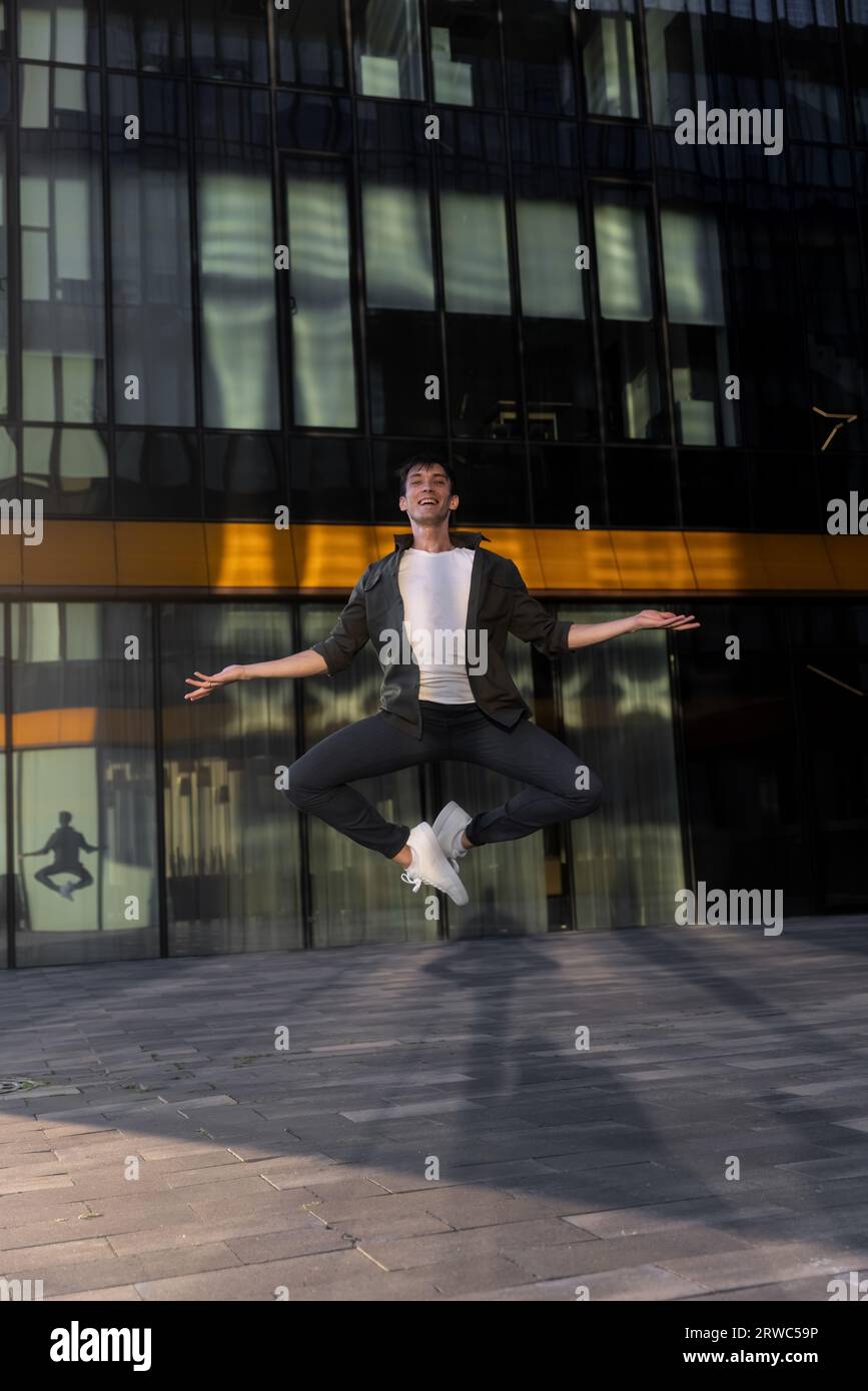 young attractive dancer in casual cloth doing ballet jump on the urban ...