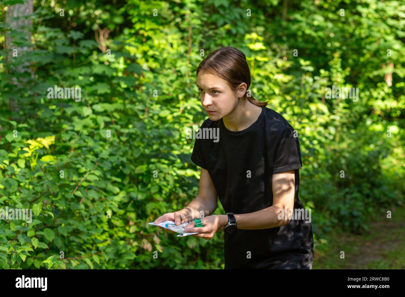 Young girl in forest reading map and searching for a control point ...