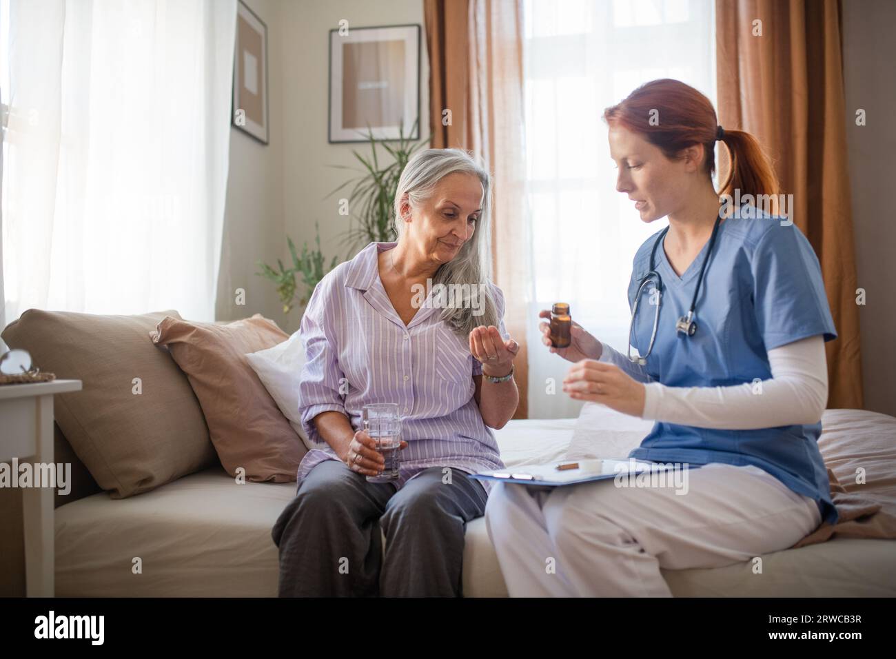 Nurse explaining senior woman how to take medicine Stock Photo - Alamy