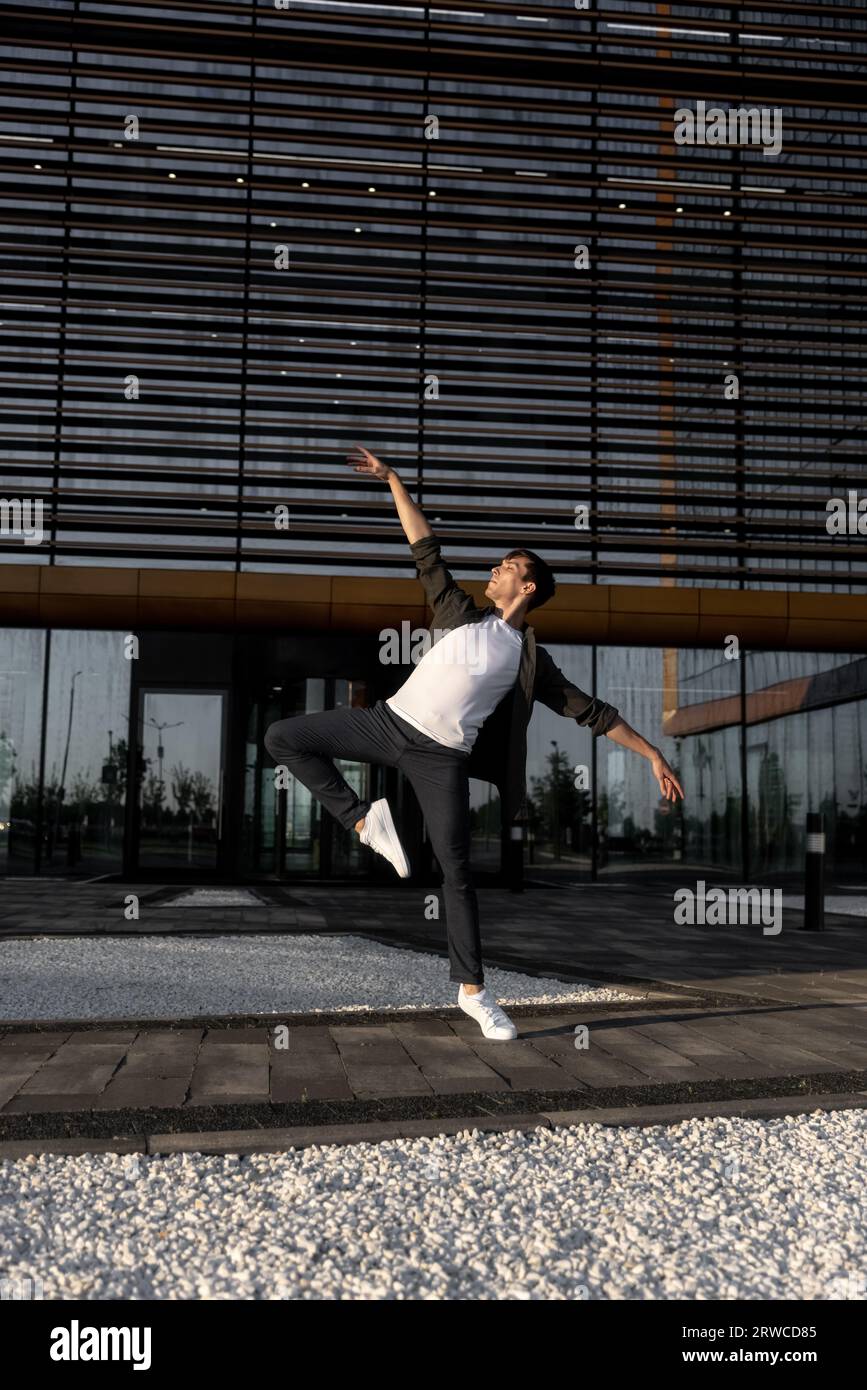 young attractive dancer in casual cloth doing ballet jump on the urban ...