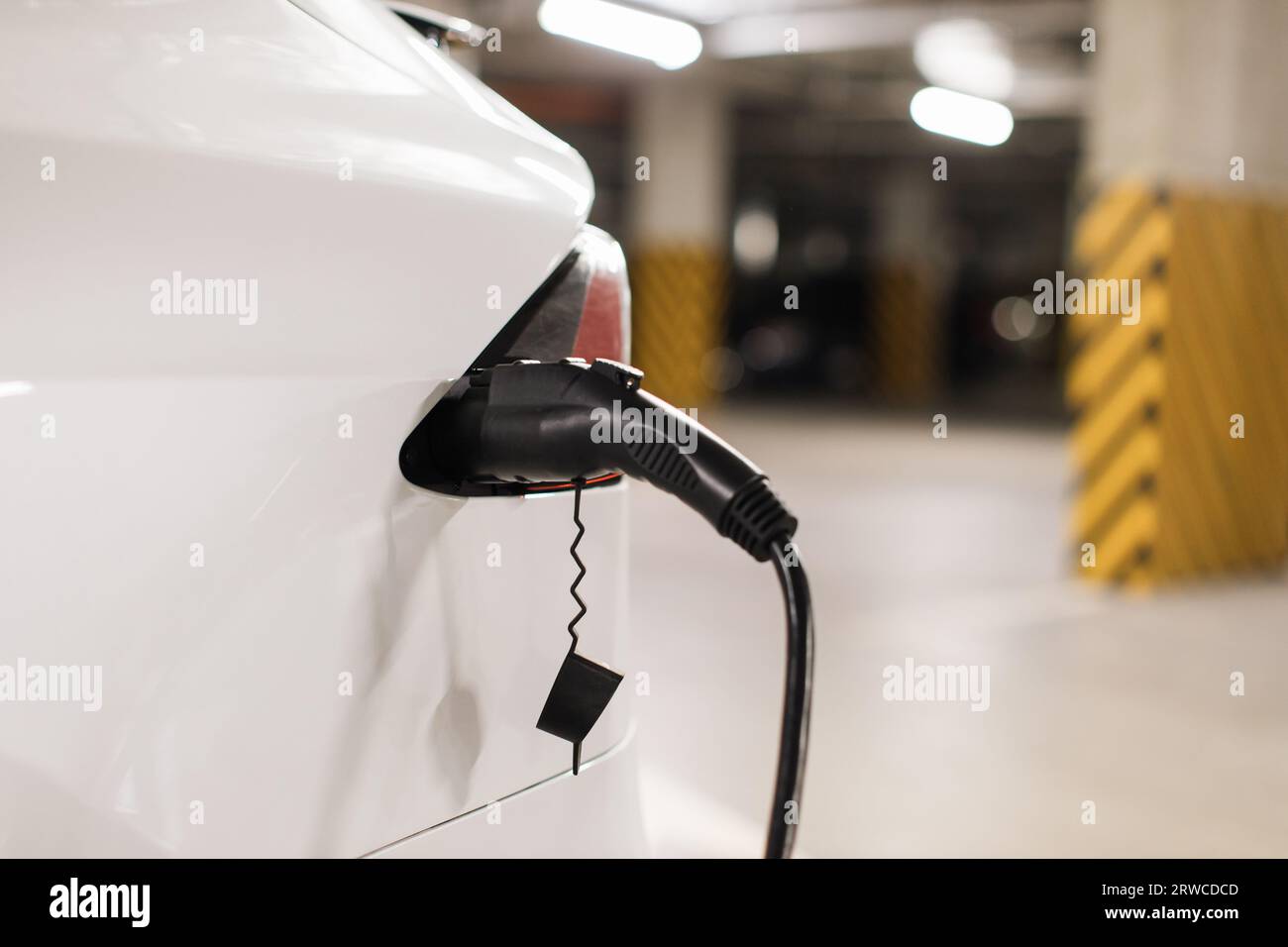 Electric car being charged in underground parking garage Stock Photo ...