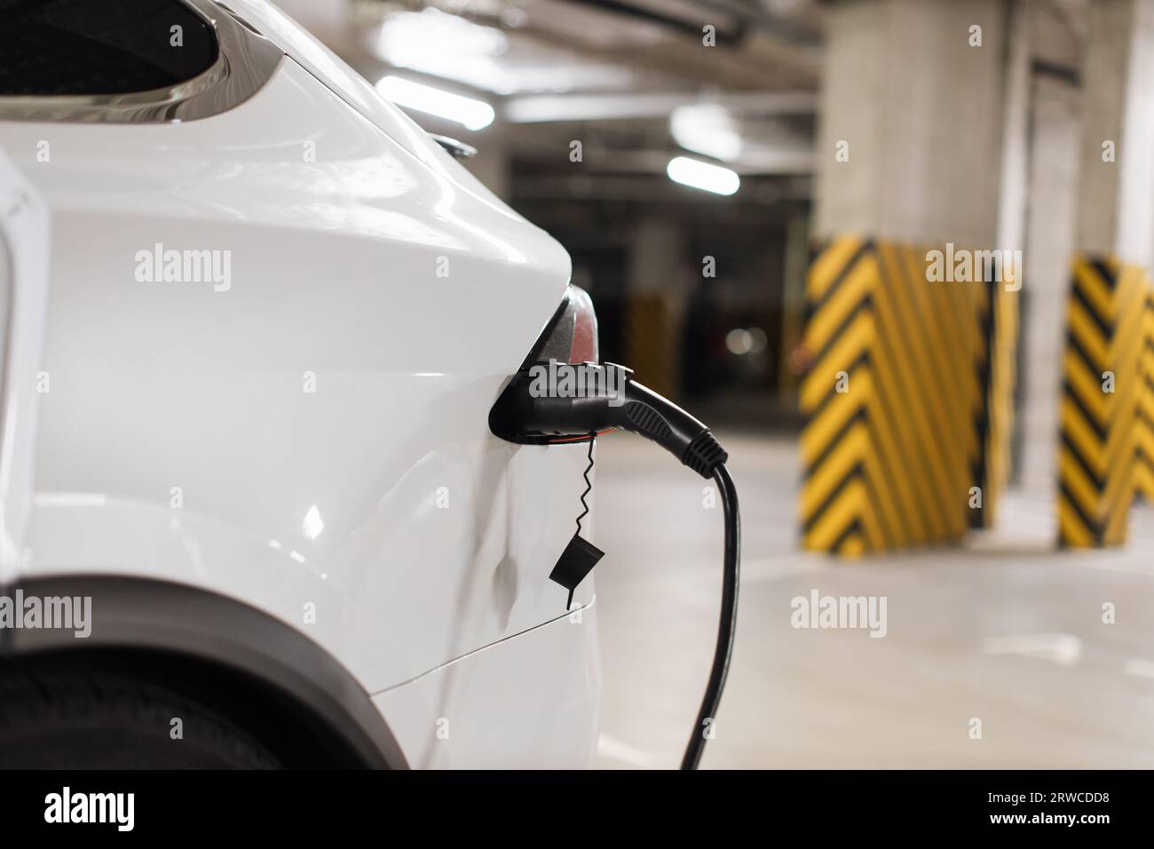 Electric car being charged in underground parking garage Stock Photo ...