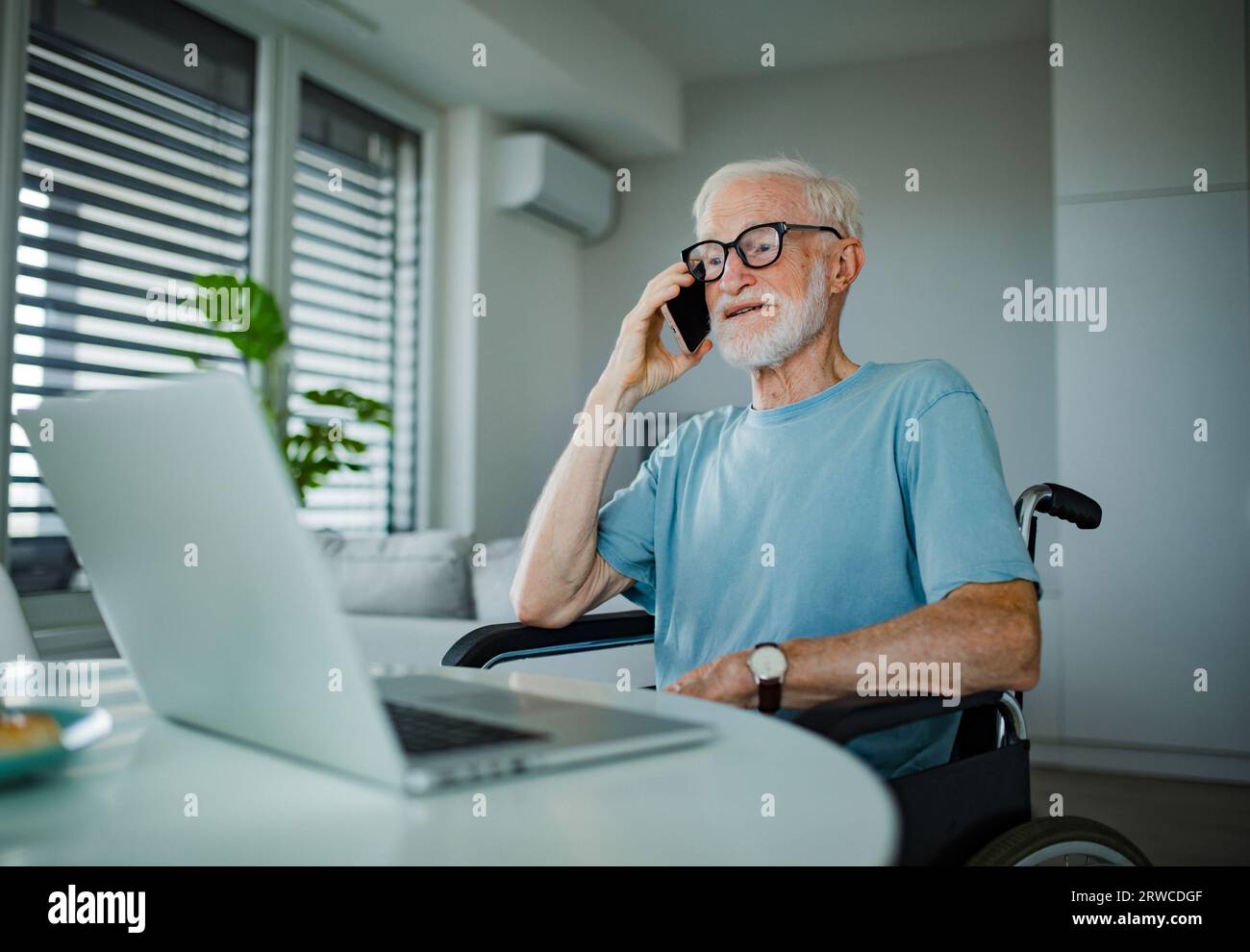 Senior man in a wheelchair working during retirement Stock Photo - Alamy