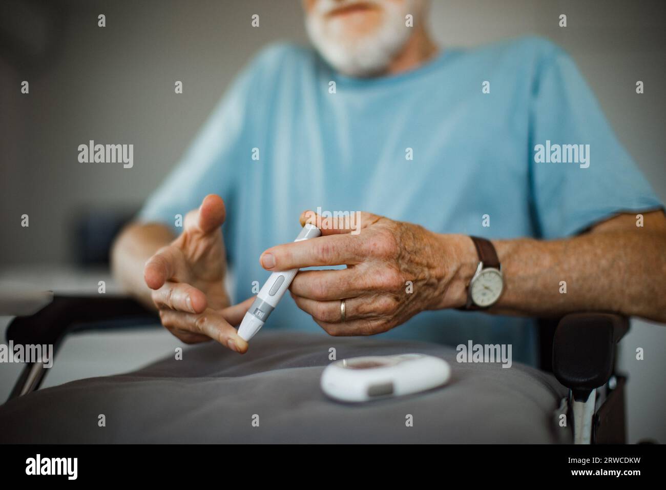 Diabetic senior man on wheelchair checking blood sugar level with ...