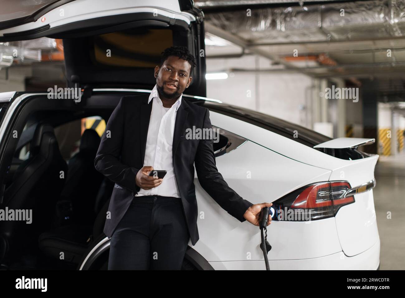 Employee with mobile starting EV charging session in parking Stock ...