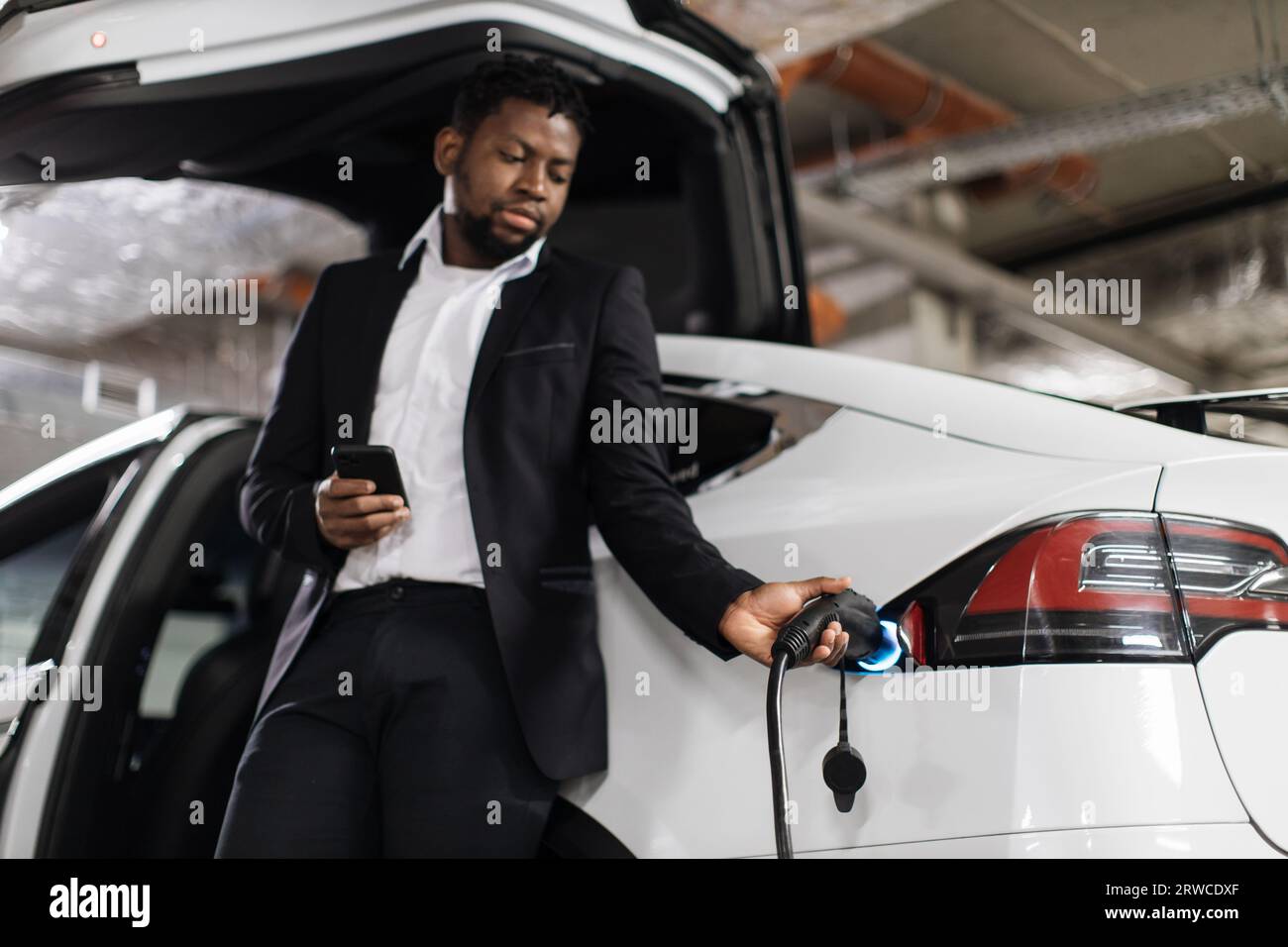 Employee with mobile starting EV charging session in parking Stock ...