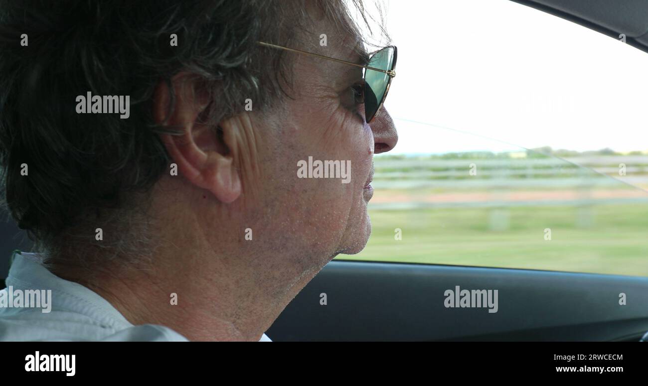 Profile of older man face driving on road with landscape passing by ...