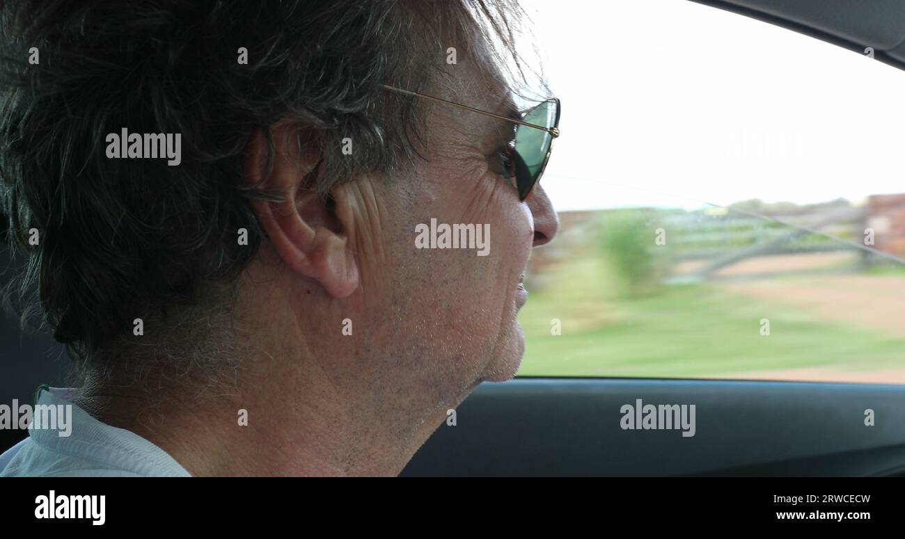 Profile of older man face driving on road with landscape passing by ...