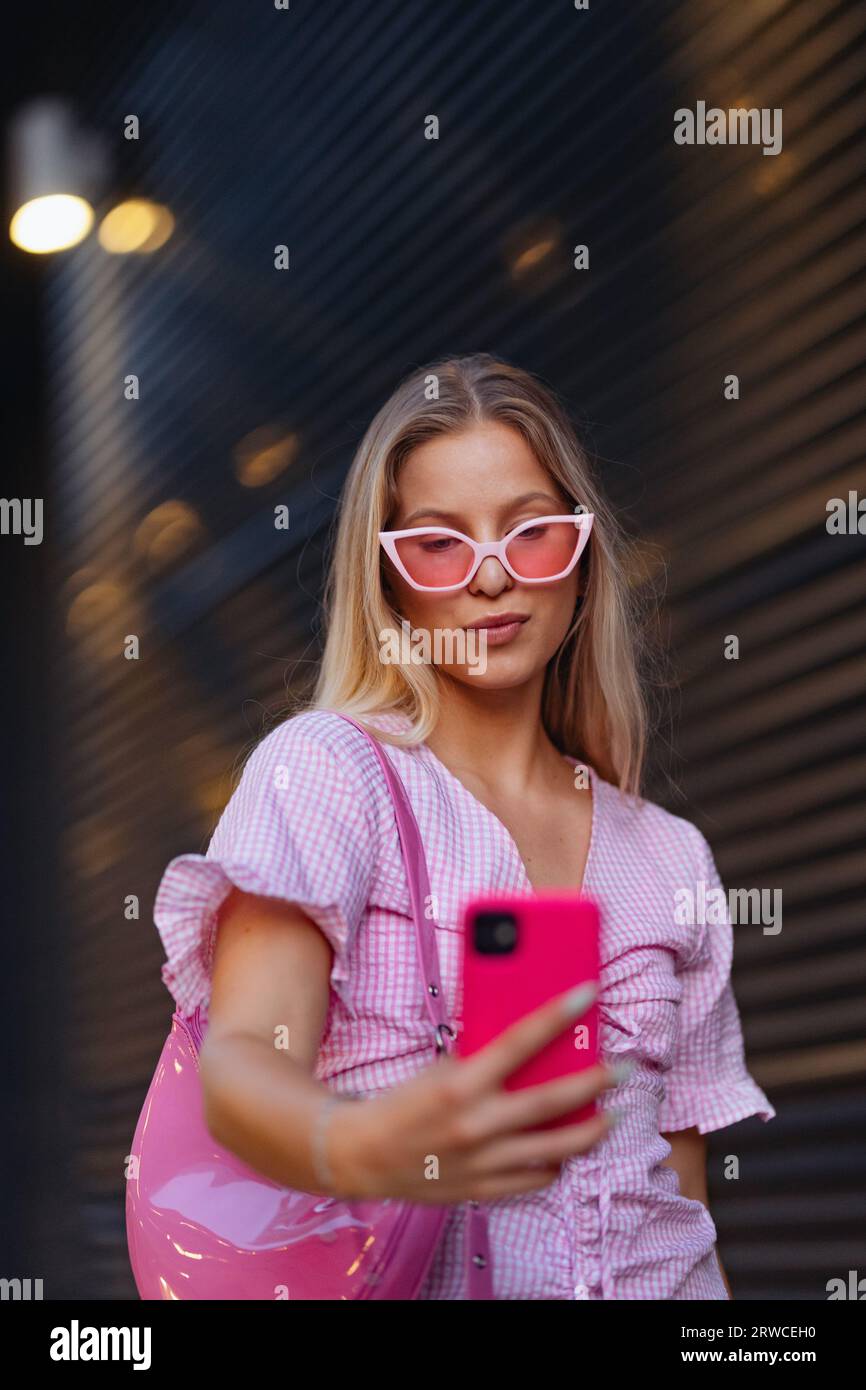 Gen Z girl in pink outfit taking selfie before going the cinema to ...