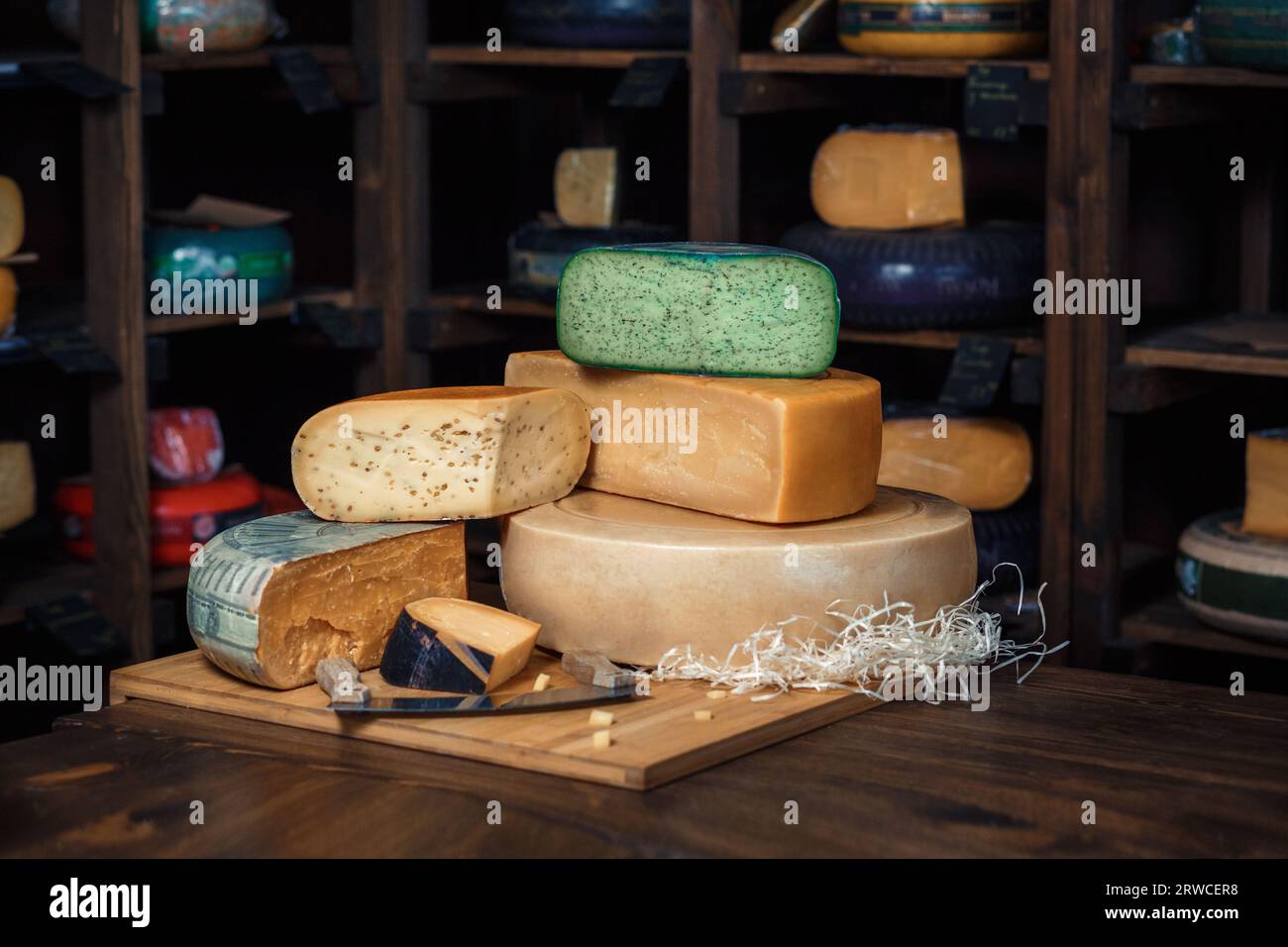 Cheese heads with slices and knives lie on a wooden board with an ...