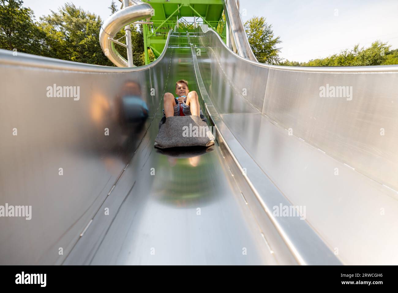 Kids go down a children's high slide at amusement park Stock Photo - Alamy
