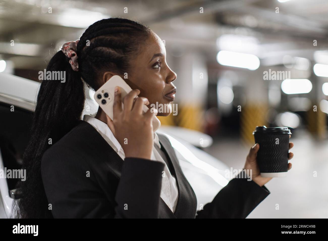 Lady with drink making call via mobile in basement parking Stock Photo ...