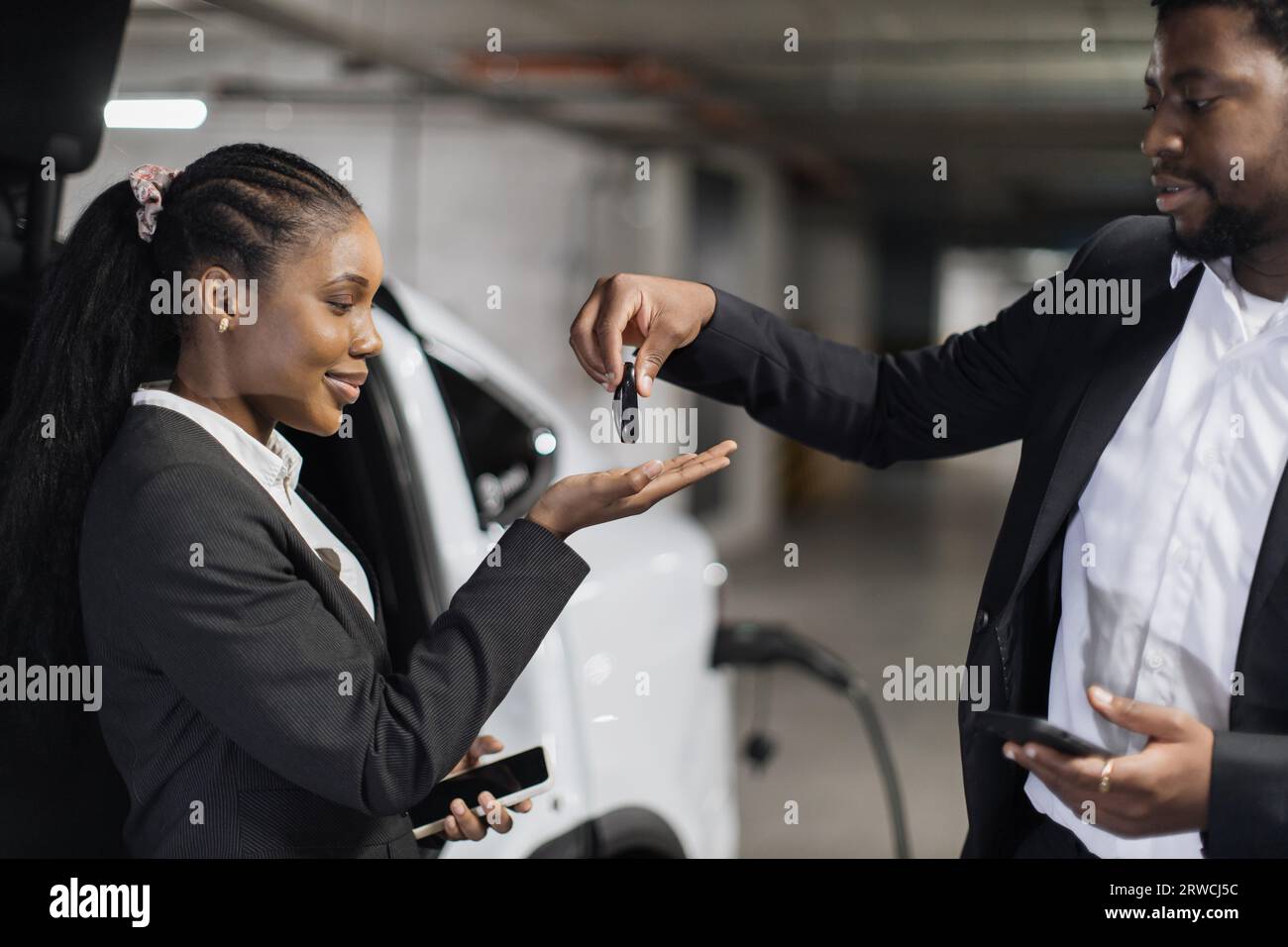 Lady receiving EV keys from male manager in basement parking Stock ...