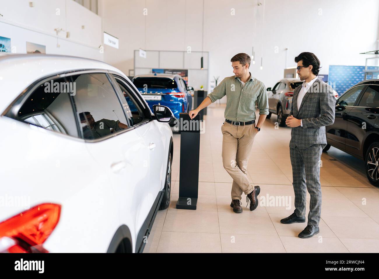 Side view of handsome customer male looking at auto and listening to ...