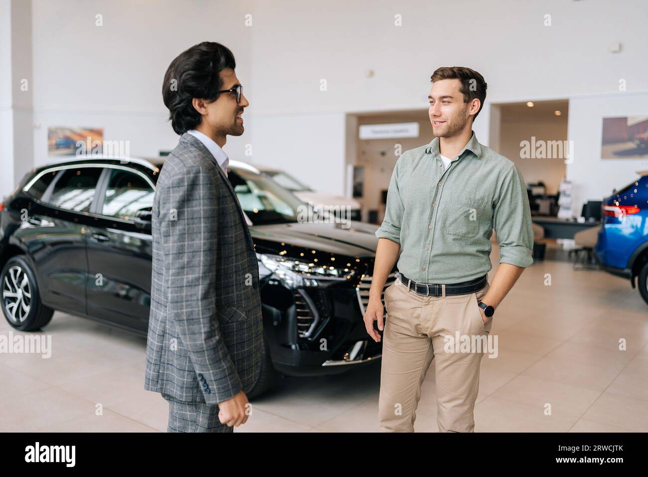 Friendly professional car dealer wearing business suit discussing new ...