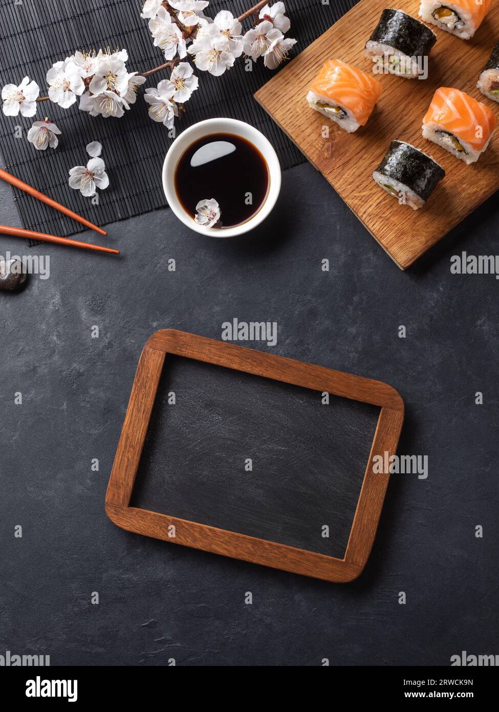 Set of sushi and maki rolls with branch of white flowers and chalk ...