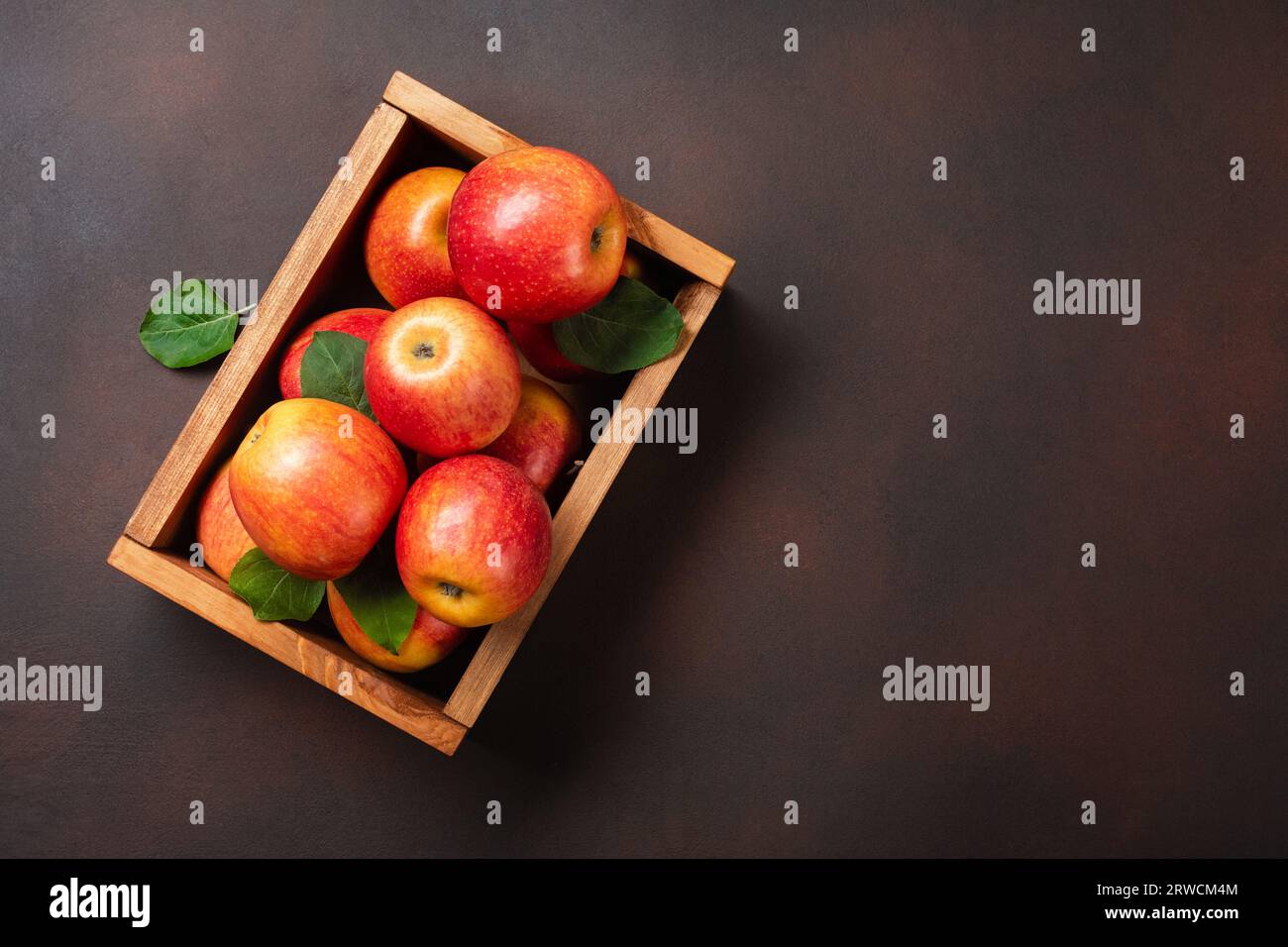 Ripe red apples in wooden box on a rusty background. Top view with ...