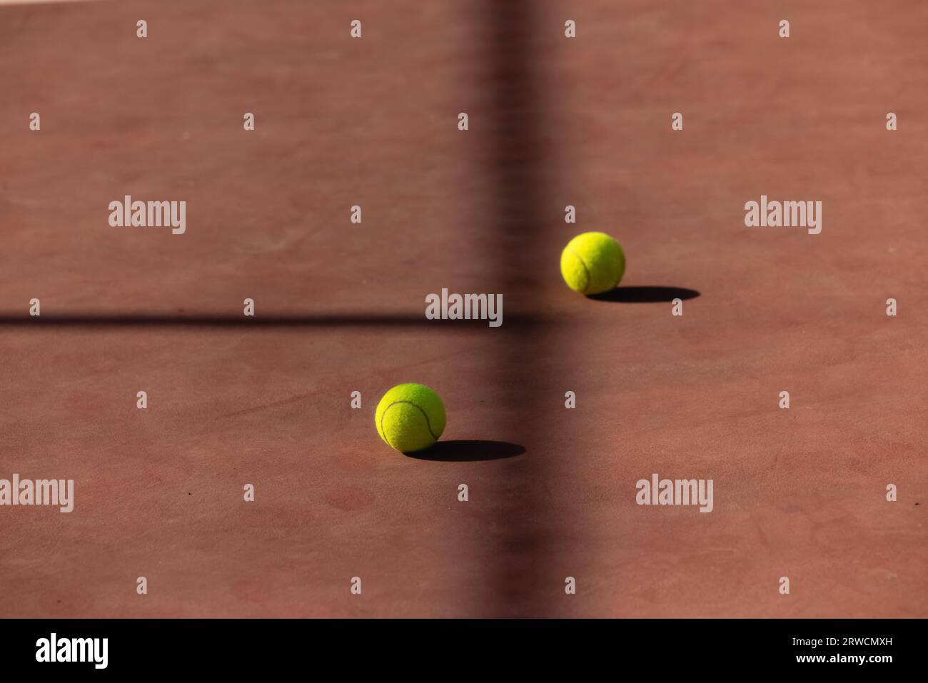 Tennis ball on clay court two separated by shadow Stock Photo - Alamy