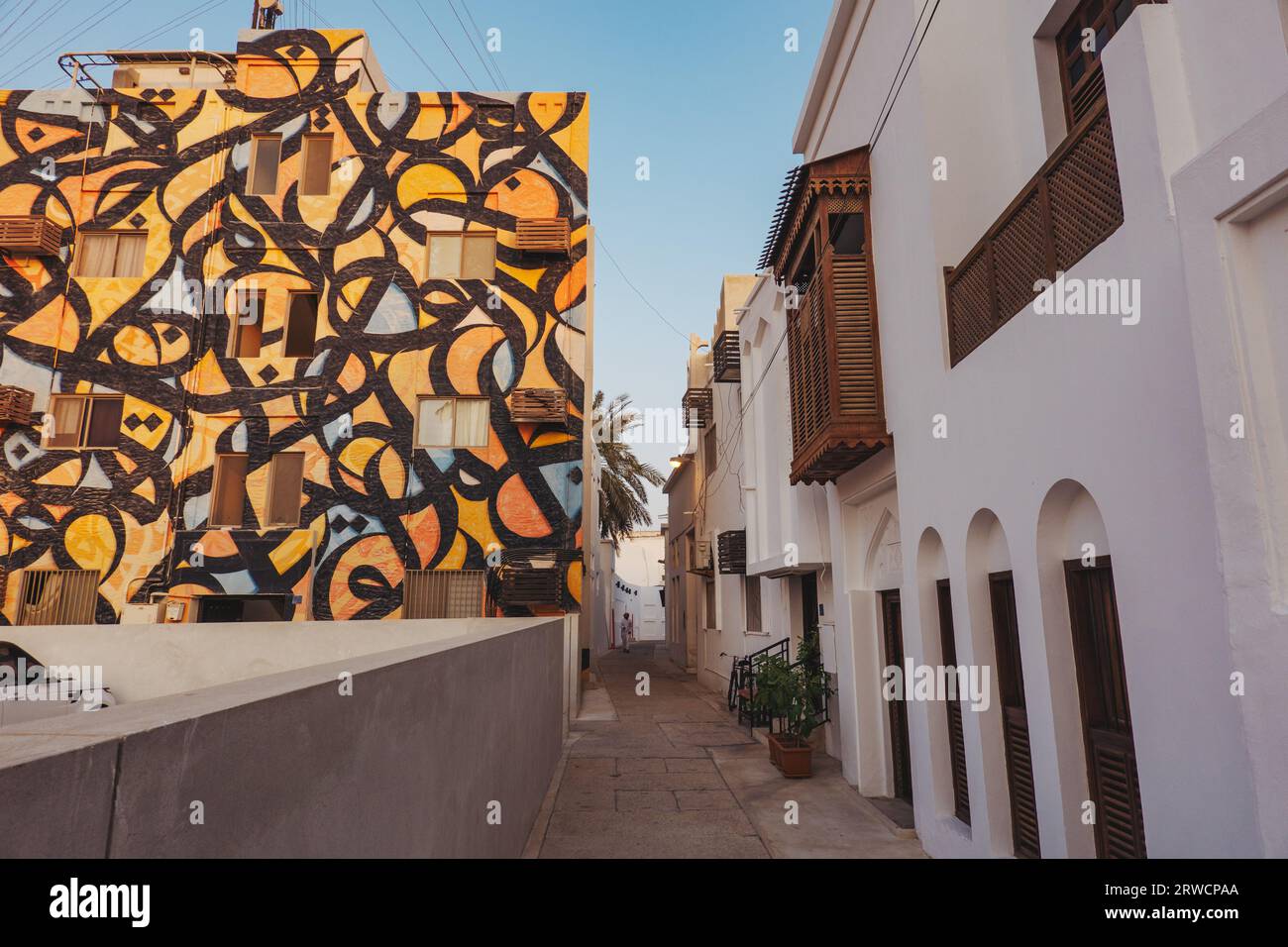 A vibrant yellow mural amongst hallmark white buildings of Muharraq, an ...