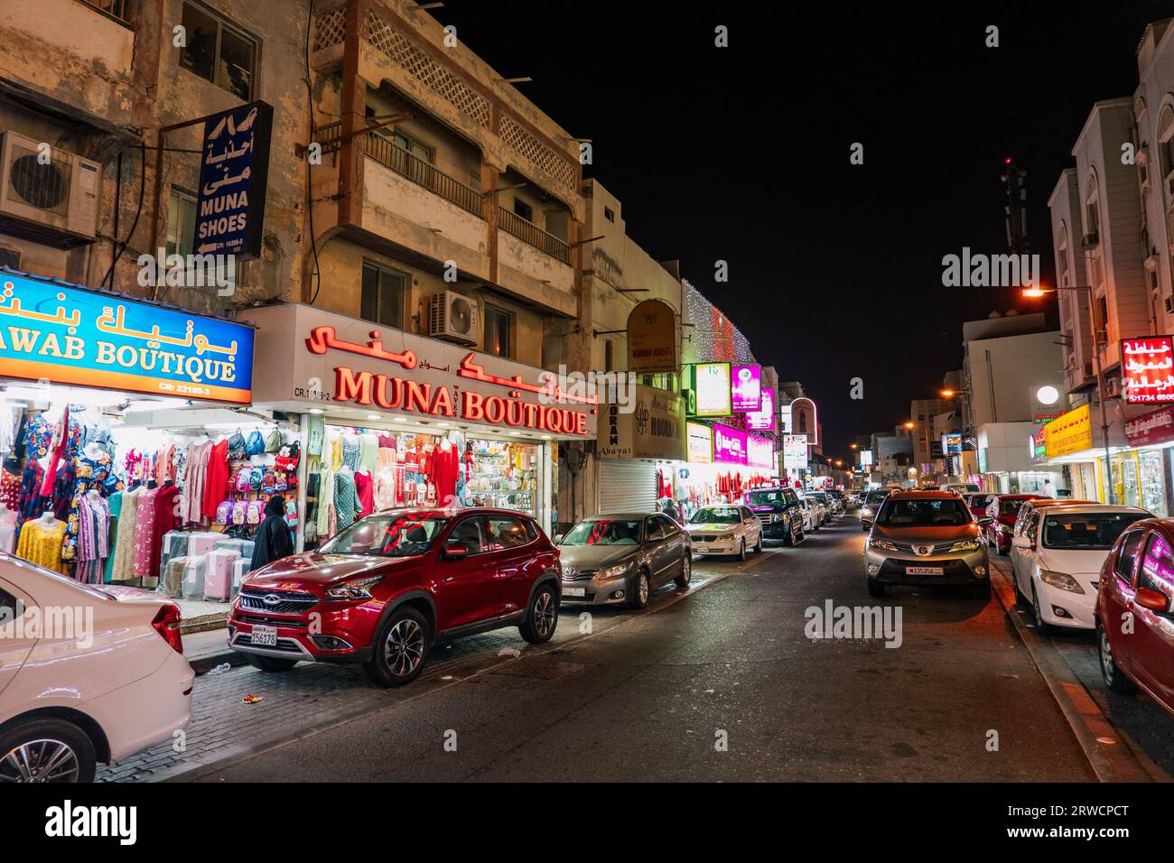 shops with bright lights and signs at night in Muharraq, a historic ...