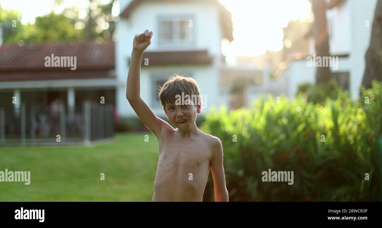Young boy raising arm in the air in celebration outdoors Stock Photo ...