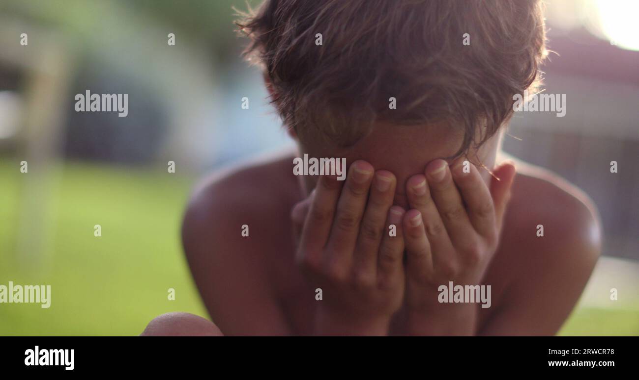 Young boy covering face feeling sad and ashamed Stock Photo - Alamy